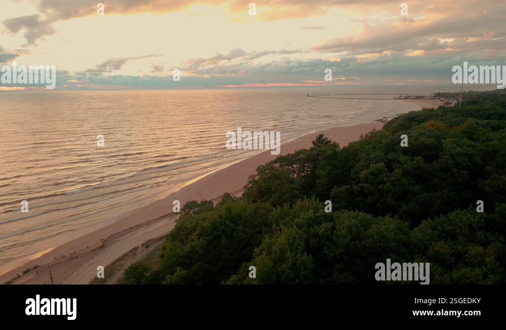 Waves lapping and cresting along the shore as the sun sets behind the ...