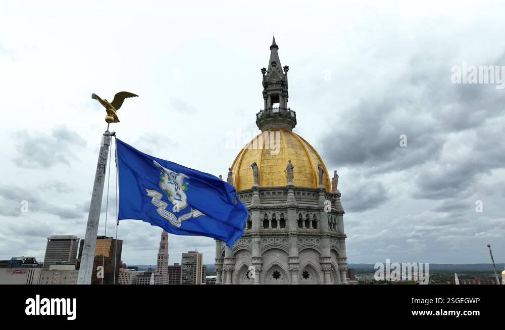 Connecticut state flag waving in breeze. State Capitol dome in Hartford ...