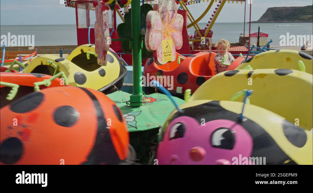 Toddler on a ladybird carousel ride at a seaside amusement park in ...