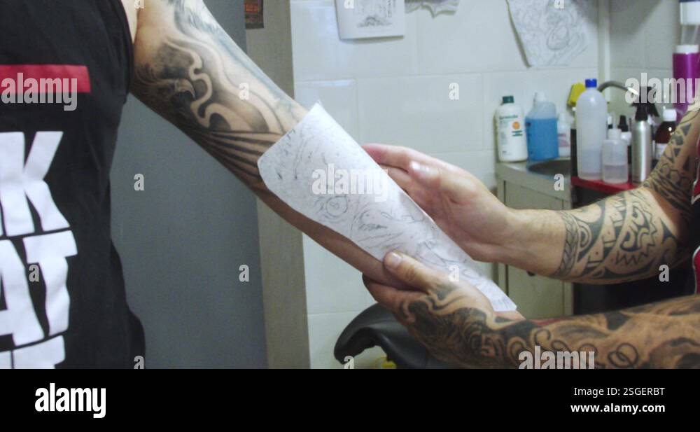 Professional tattoo artist places the tracing of the design on the arm ...