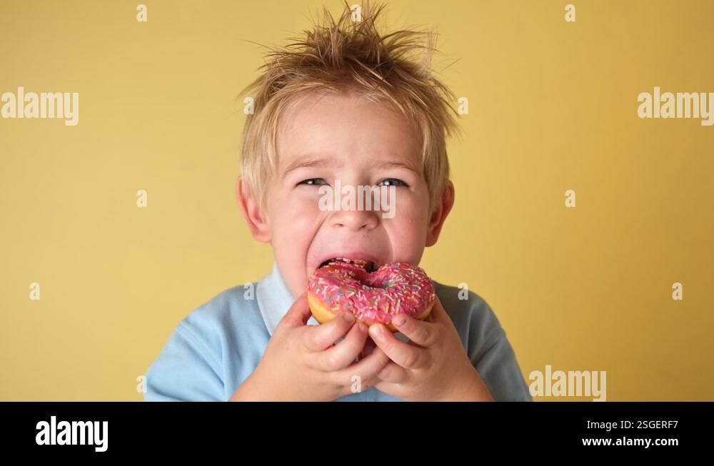 Happy Child eating glazed donut. Little boy is biting and chewing donut ...