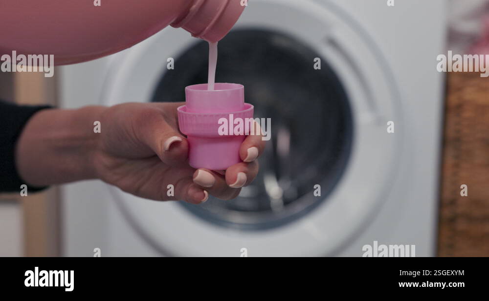A woman pours detergent into a stopper in the background of a washing ...