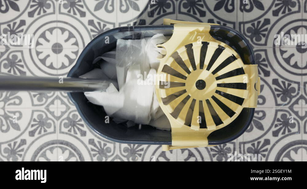 Squeezing out a mop after mopping the floor in a bucket. Top view close ...