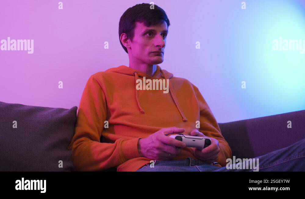 Young gamer man playing video game on TV with modern console in neon ...
