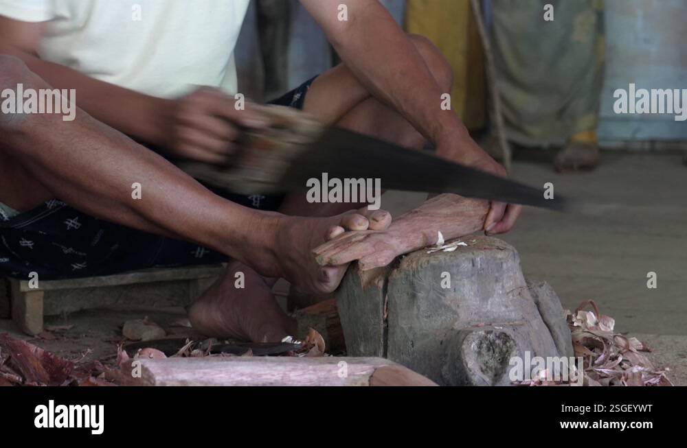 Lemo, Toraja, Indonesia 07042022-Man saws arm of wooden Tau Tau effigy ...