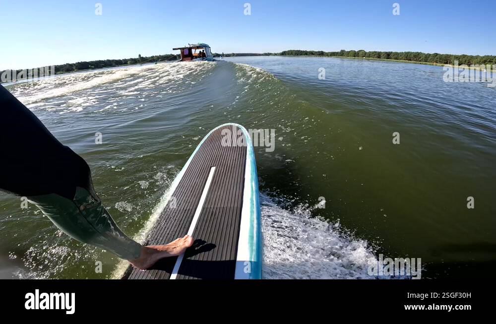surfer on longboard in wave behind boat Stock Video Footage - Alamy