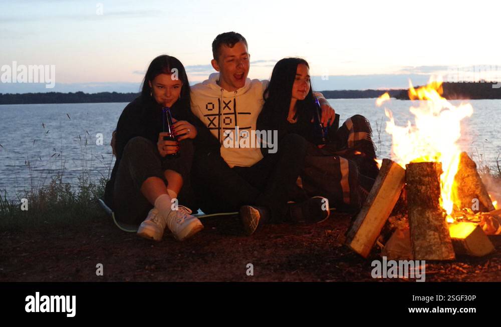 Three friends singing while sitting down next to a campfire Stock Video ...
