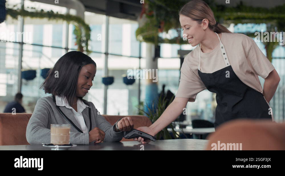 A woman pays for coffee at a restaurant using a smart watch. The ...