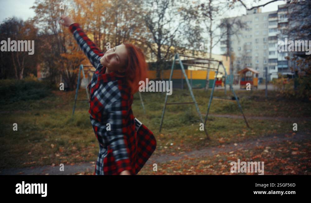 Spinning around a twirling cheerful redhead girl in a city autumn ...
