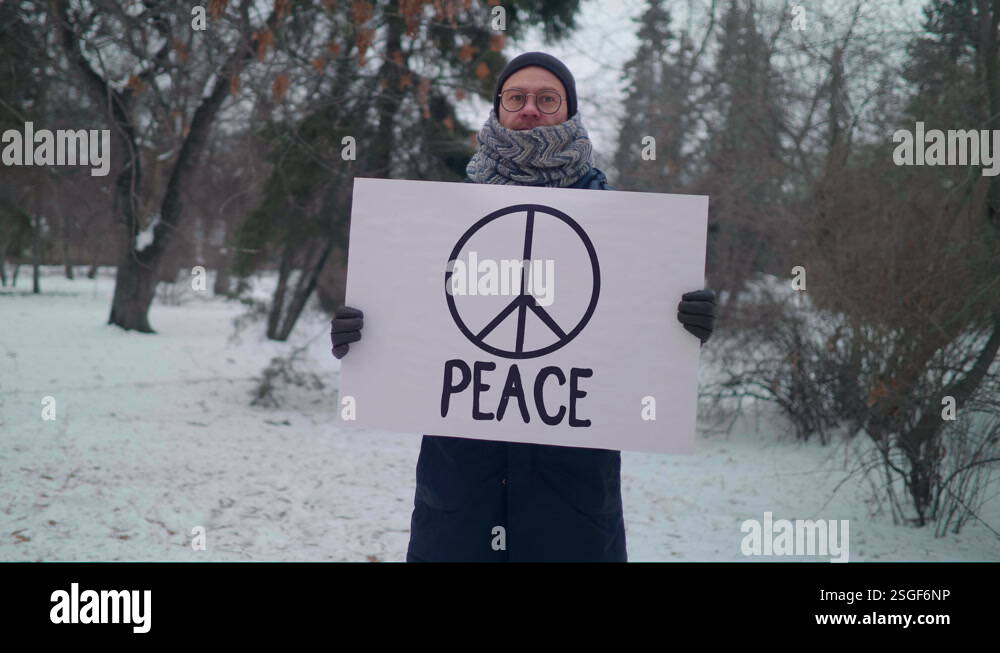 A male activist in a single picket holding a white banner with a Peace ...