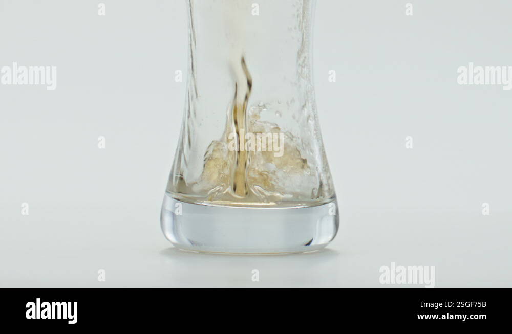 Fresh golden beer flowing on glass at white background closeup. Wheat ...