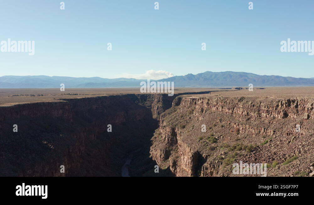 Aerial of desert river gorge with large wildfire burning in distant ...