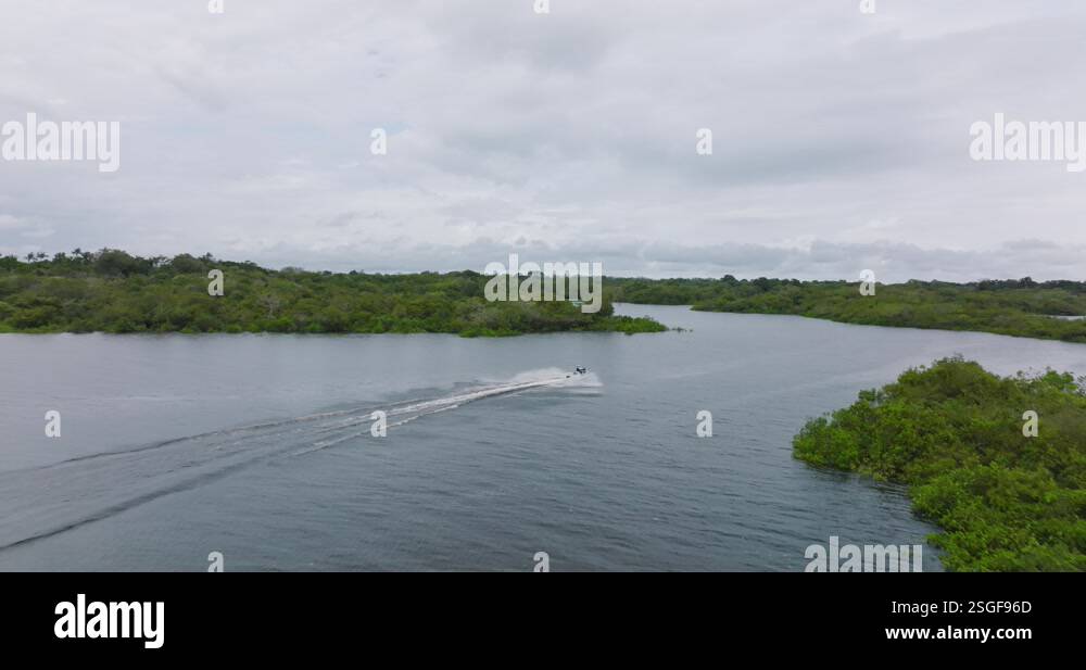Aerial tracking shot of jet ski sailing on Rio Negro waters on cloudy ...