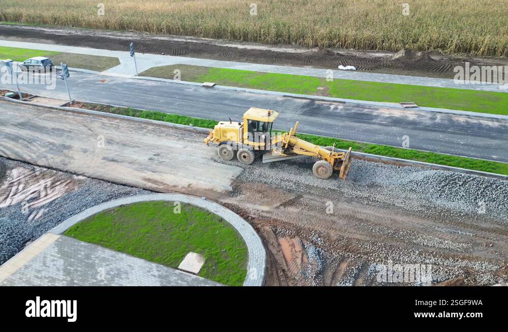 A powerful grader is leveling the road at a construction site Stock ...