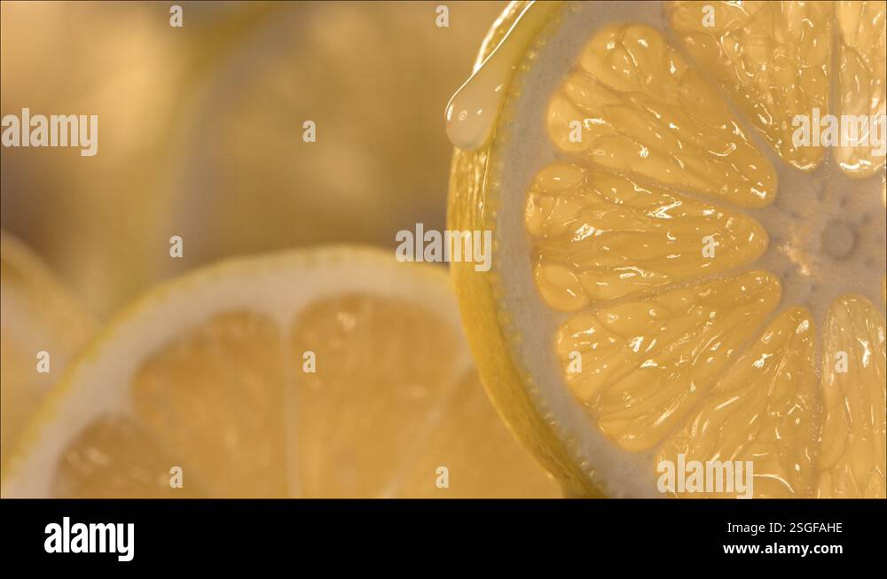 Drop of Lemon Juice flow down the surface of a ripe juicy Lemon slice ...