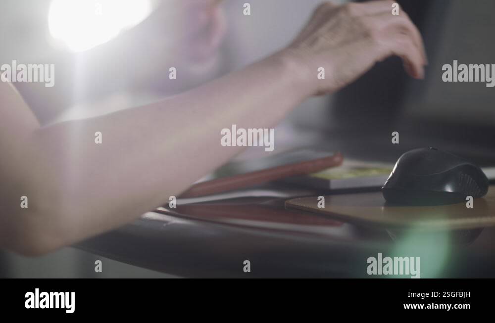 Female working on her laptop computer, scrolling on her mouse, holding ...