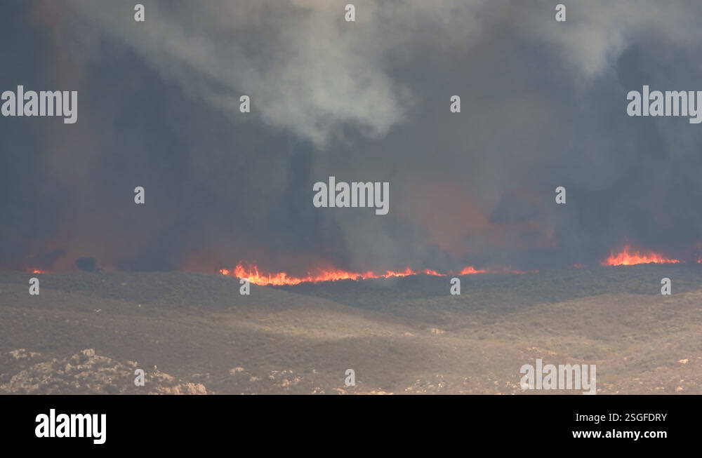 Masses of dense black smoke filling the air with a wildfire burning ...