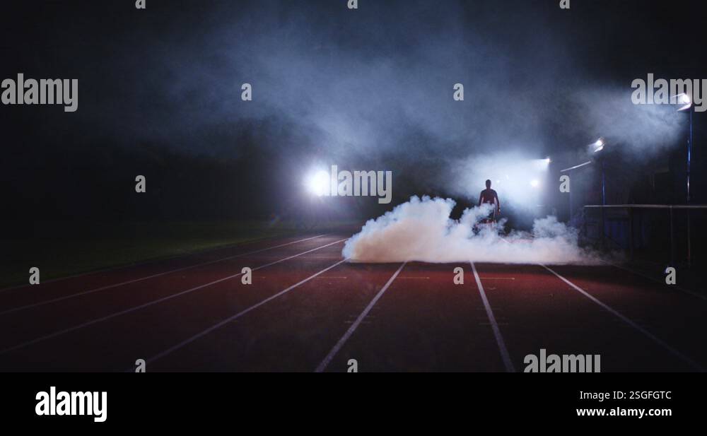A Man is walking and fog comes out of a fog machine in a sports stadium ...