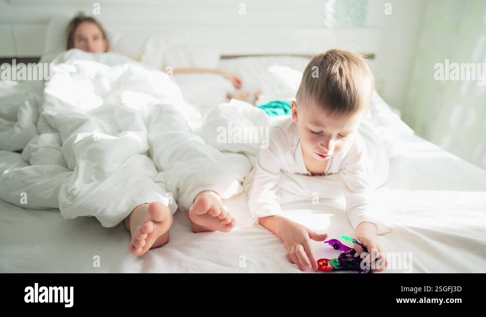 Home life brother and sister or mother in bedroom lie on bed with white ...