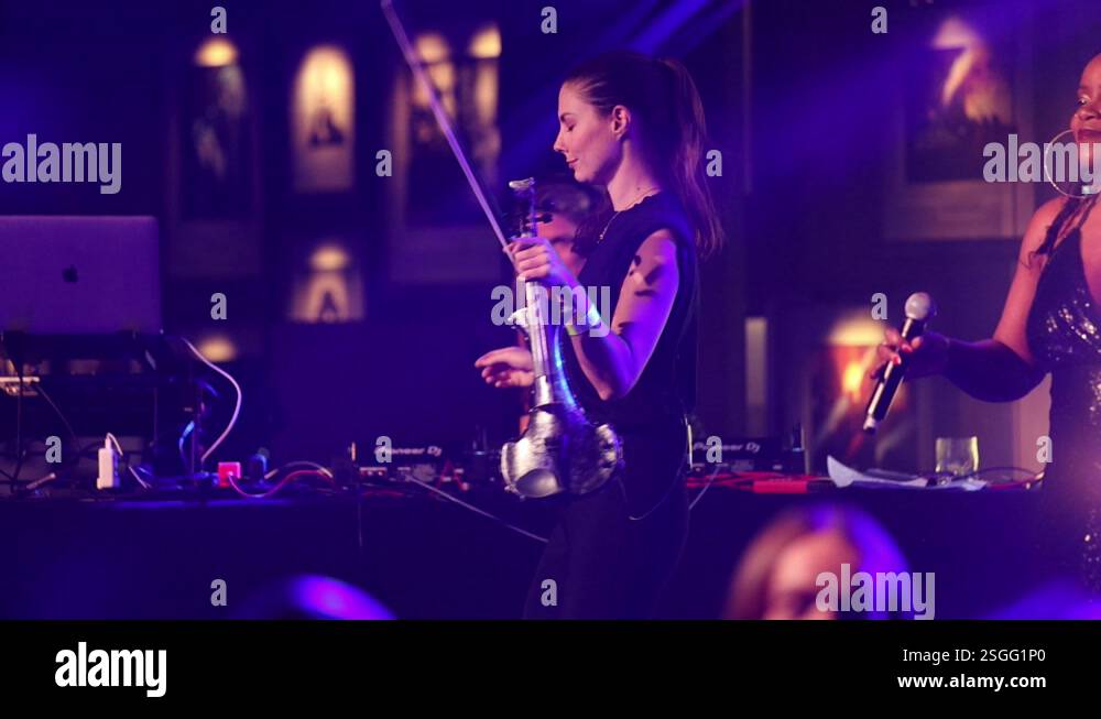 Attractive woman with violin dancing to rhythm on stage with bight ...