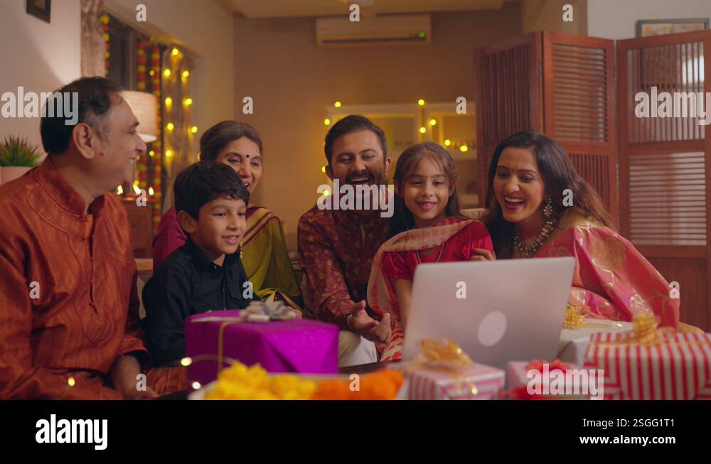 Indian close-knit family watching online movie together on laptop ...