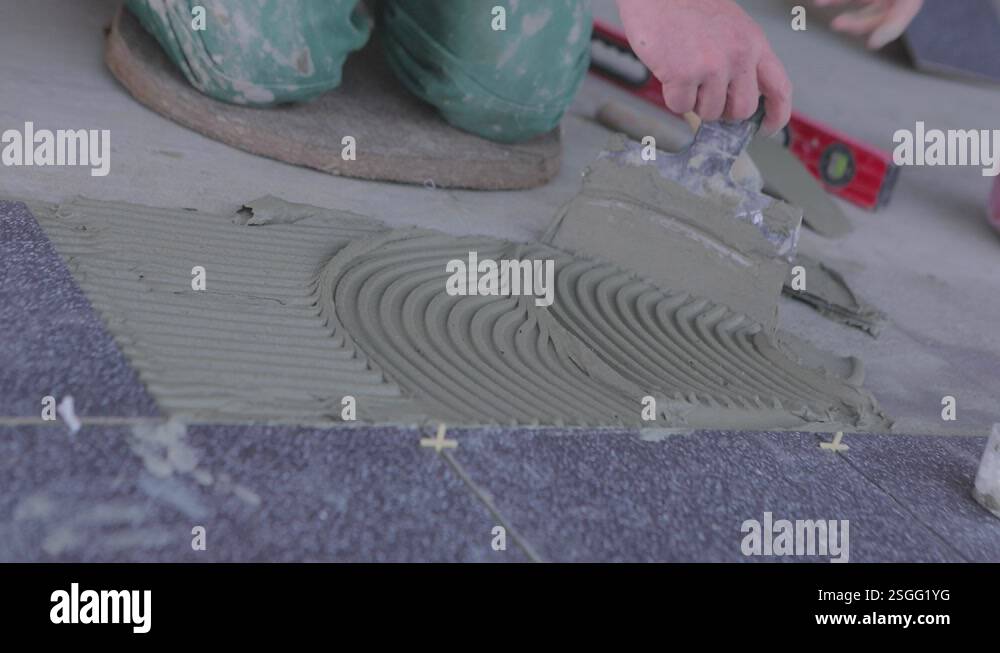 Construction worker laying tiles on the floor for mortar. The builder ...