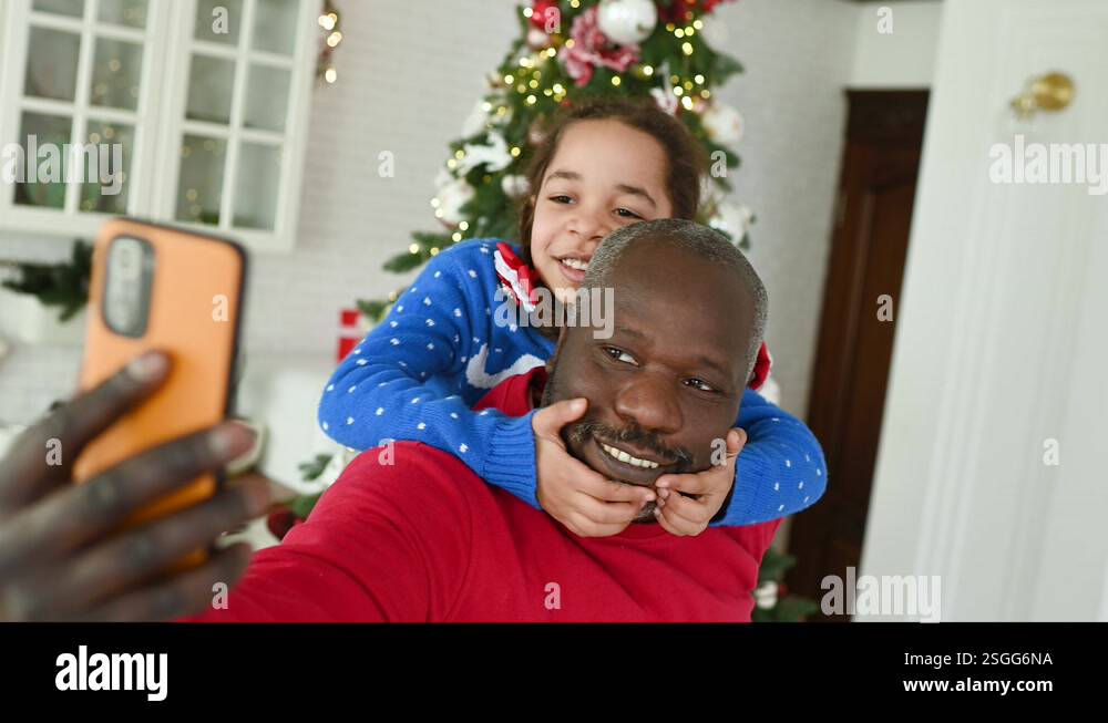 little daughter sitting on the shoulders of her dad smiles while ...
