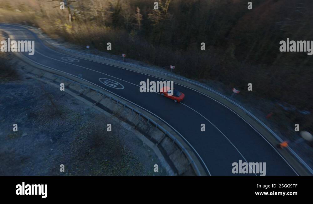 FPV drone dive red sport car driving turn on serpentine asphalt road ...