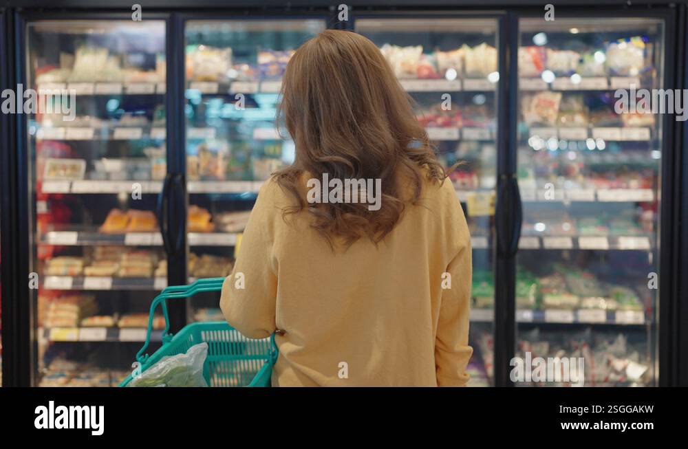 Back view of woman shopping frozen food in front of refrigerator in ...