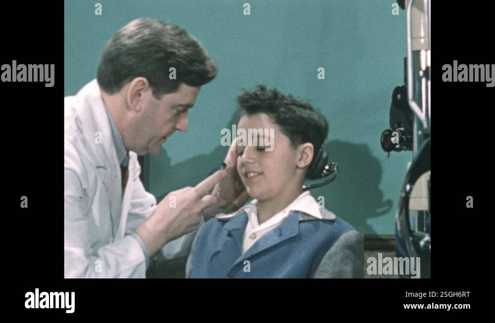 1950s: Doctor looks in boy's eye. Reflection on girl in mirror, hands ...