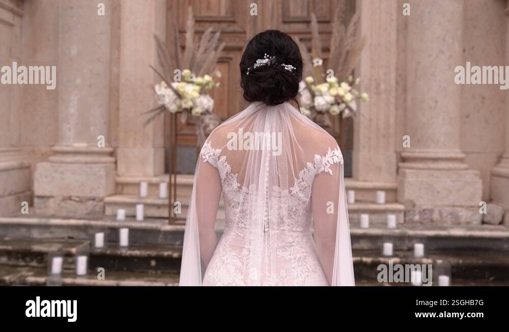Bride in a white dress with a veil goes to the entrance of the church ...