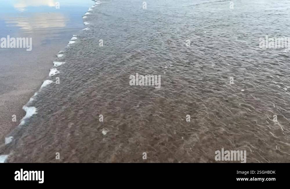 Slow motion video of water of tide rolling on wet sand on seaside ...