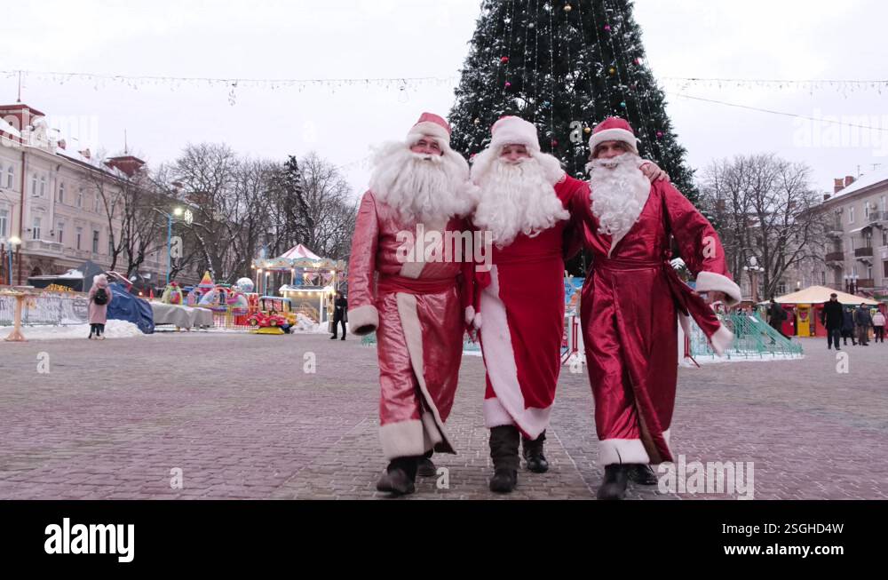 A group of Santa Clauses walk in the center of the city, behind them ...