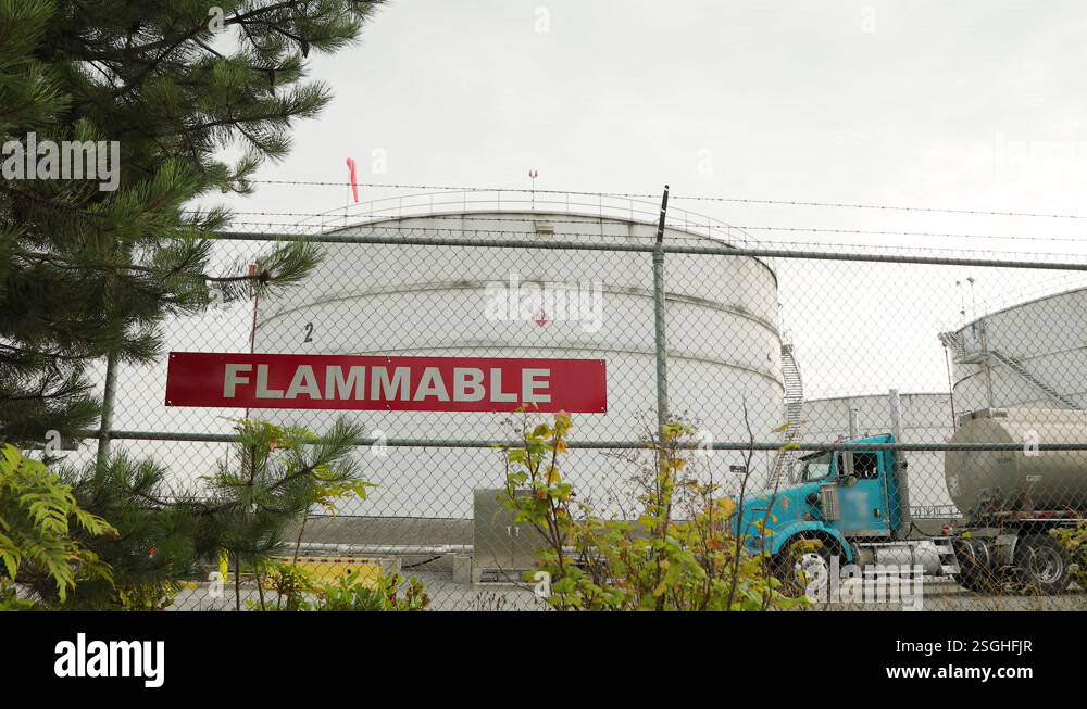 Large jet fuel or oil storage tanks behind a chain link fence with ...