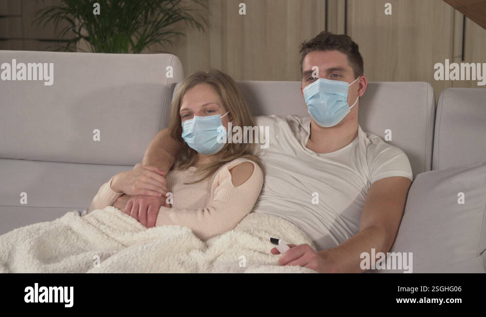 CLOSE UP: Couple wearing protective face masks and watching TV during ...