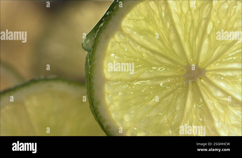 Drop of Lime Juice flow down the surface of a ripe juicy Lime slice ...