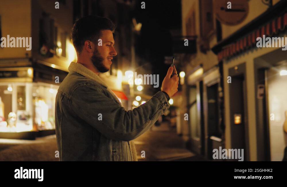 Male having video conference call on the street in darkness at night ...