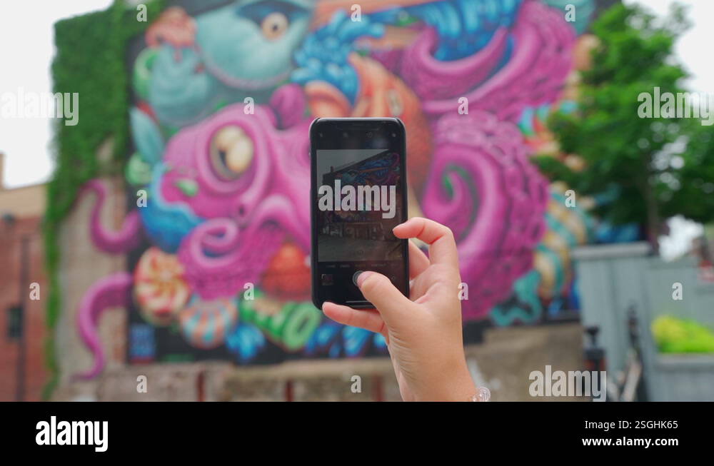 Woman holding iPhone taking a photo of mural in the city Stock Video ...