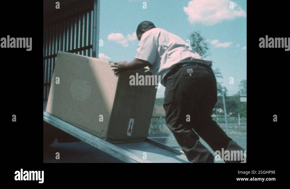 1990s: Wheelbarrow pushed up ramp into house. Man pushing large box up ...