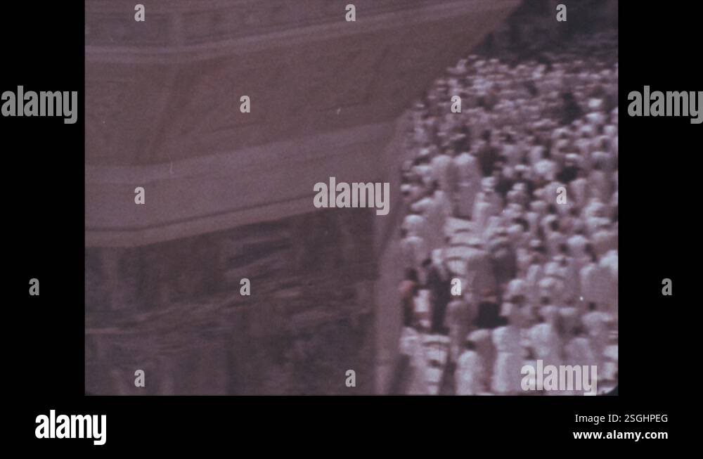 1980s: Pan across crowd praying in mosque. Crowd around wall, men ...