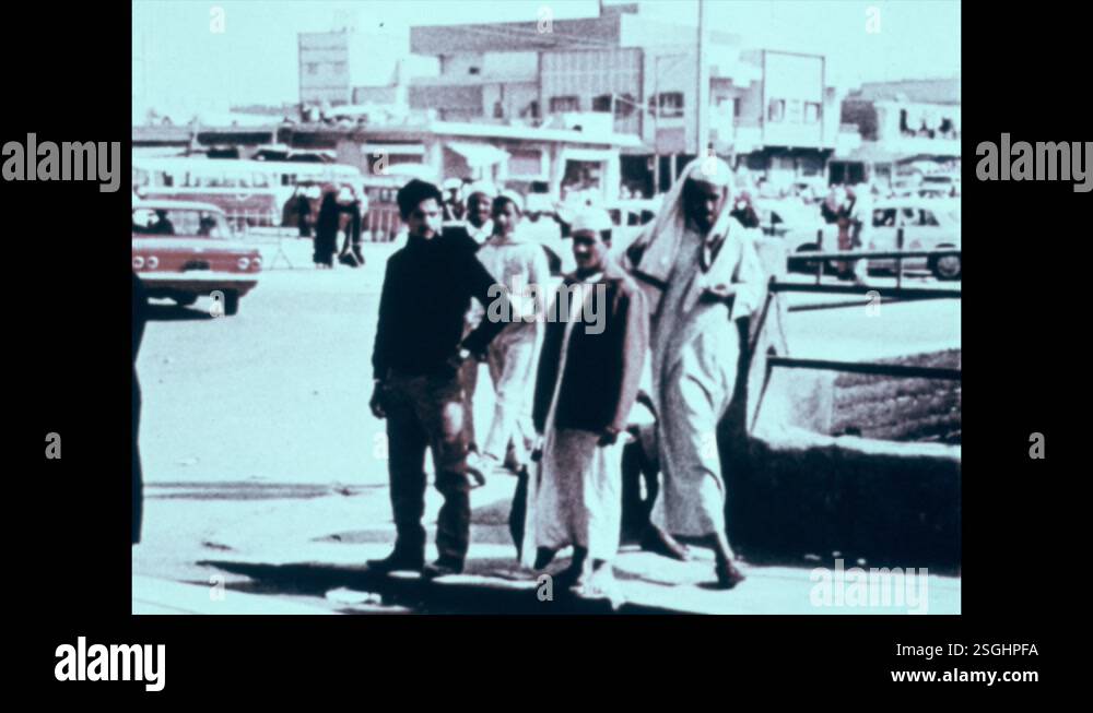 1980s: High angle of intersection. Men on corner, traffic passing ...