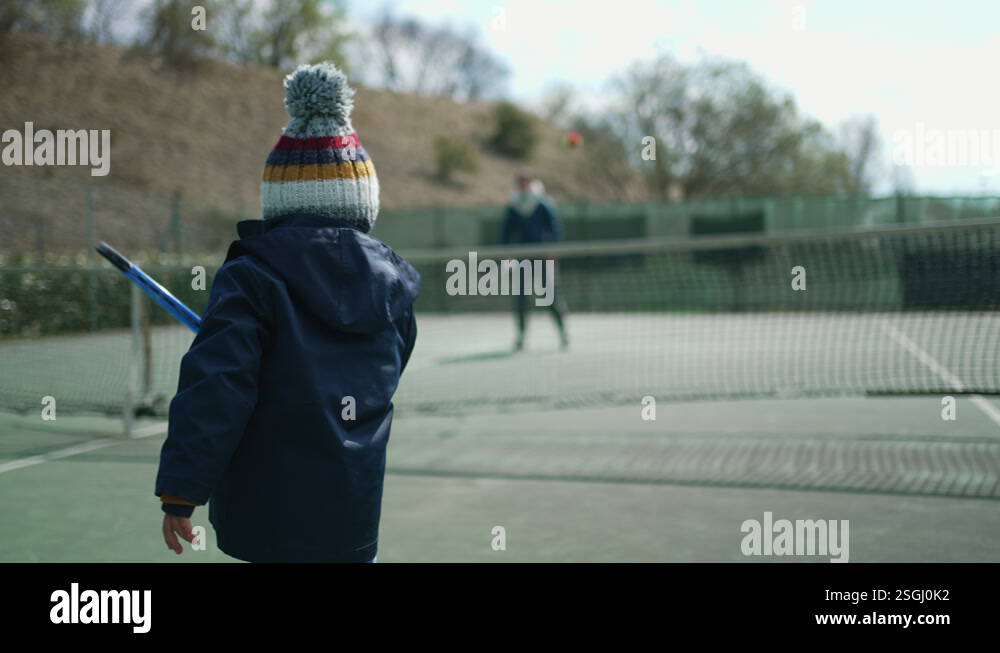 Back of kid playing tennis with parent during winter season. Child ...