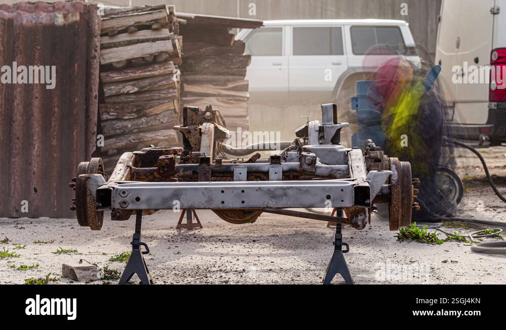 Repairman working on Old Car Chassis, Sandblasting the damaged steel ...
