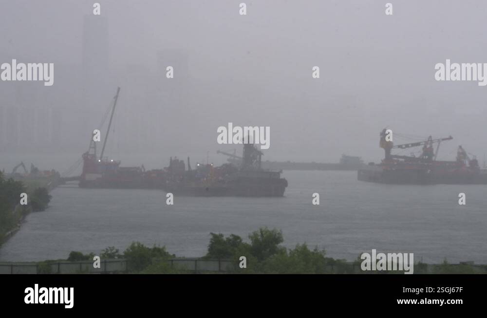 Ships are seen at the waterfront under heavy rain during a severe ...