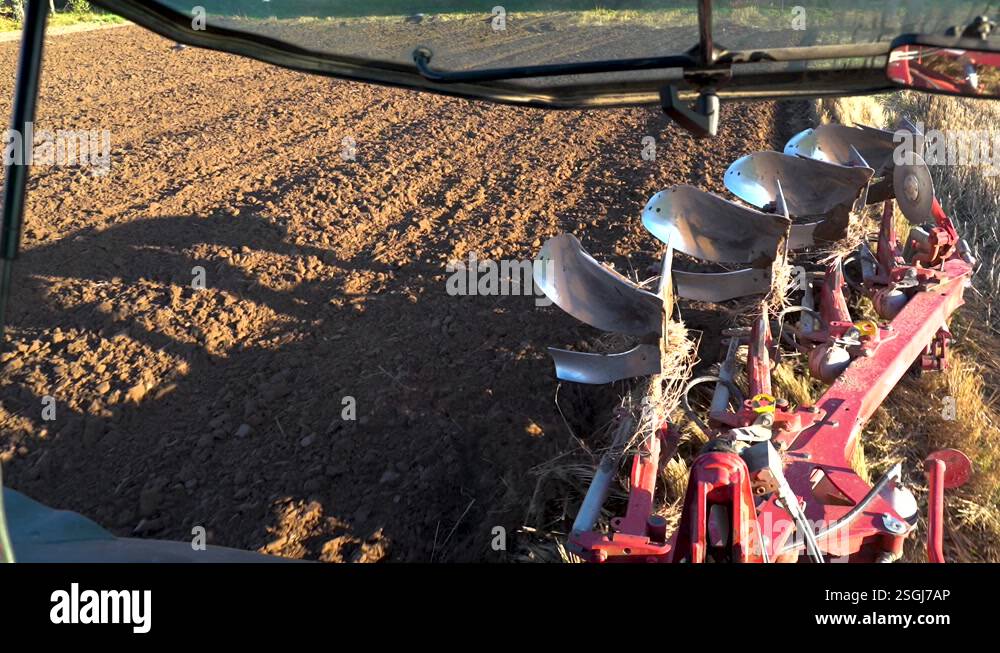 Tractor pulling reversible plough on the field, cultivating soil for ...