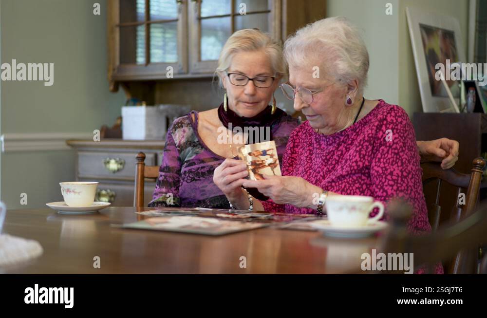 Camera pulls back from senior elderly smiling woman looking at old ...