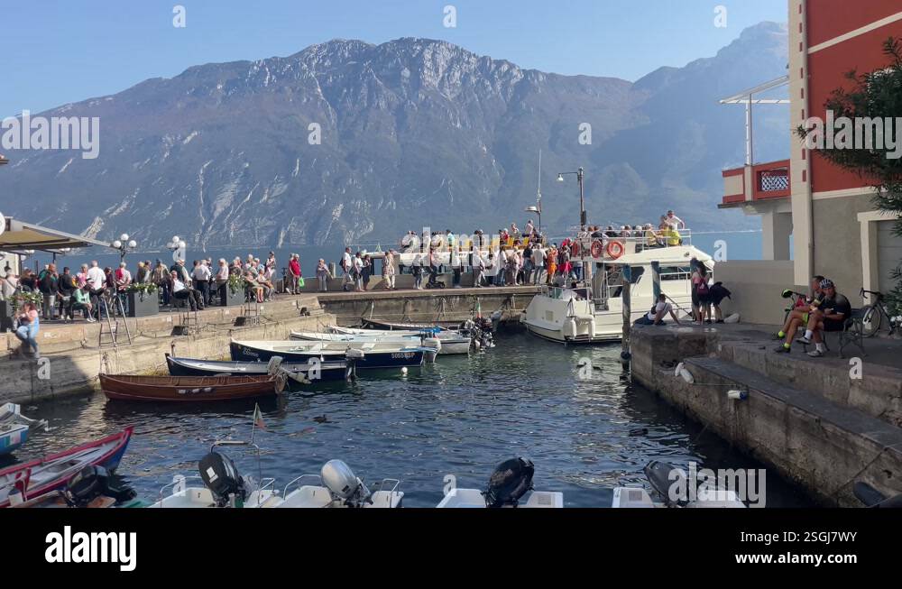 People boarding crowded boat in marina for sightseeing tour, Lake Garda ...