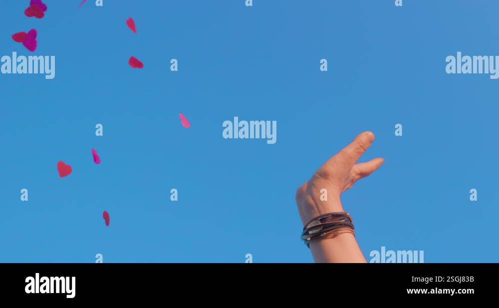A woman is throwing beautiful paper heart confetti in the air and ...