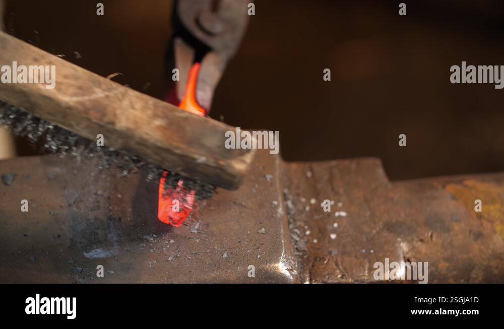 Blacksmithing. Using a wire brush and tongs to clean a red hot billet ...