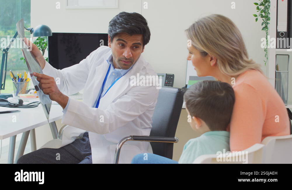 Doctor In White Coat With Mother And Son In Office Looking At MRI Or CT ...